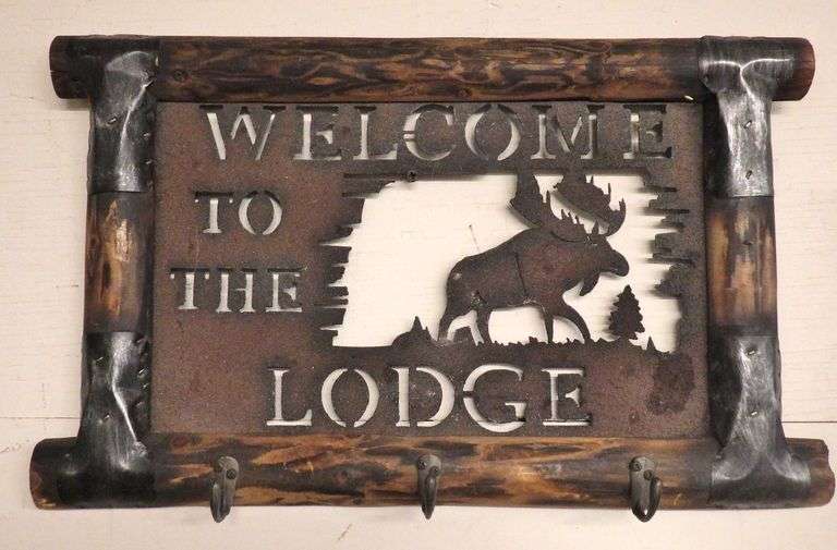 Metal "Welcome To The Lodge" sign with wood frame, has four hooks to ...