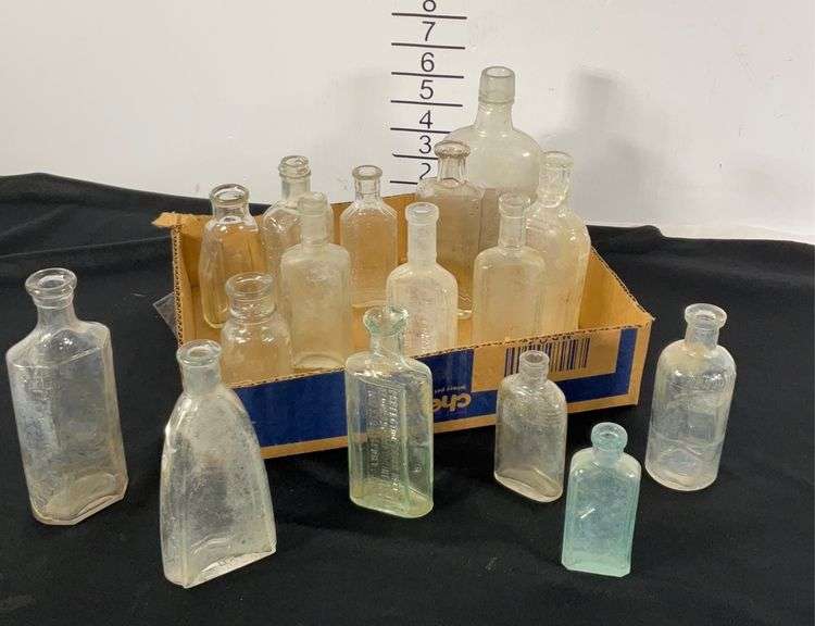 Flat of old clear medicine bottles. One is cracked and a couple are ...